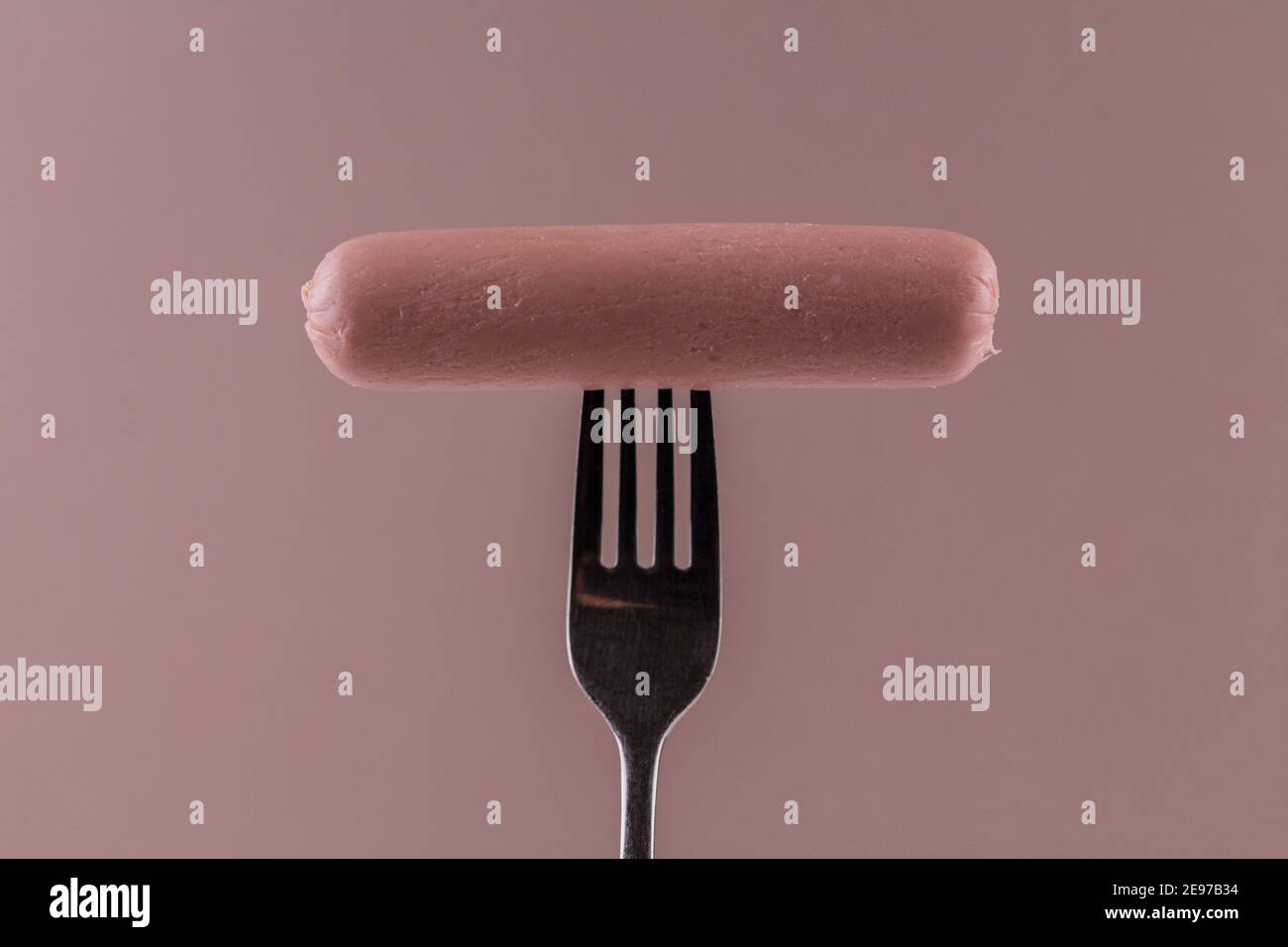 a pink sausage on an iron fork on the background in the kitchen fast ...