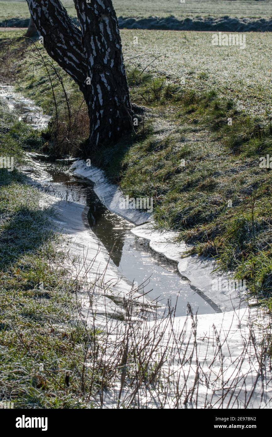 The trench is frozen over and covered with ice. It is winter and severe ...