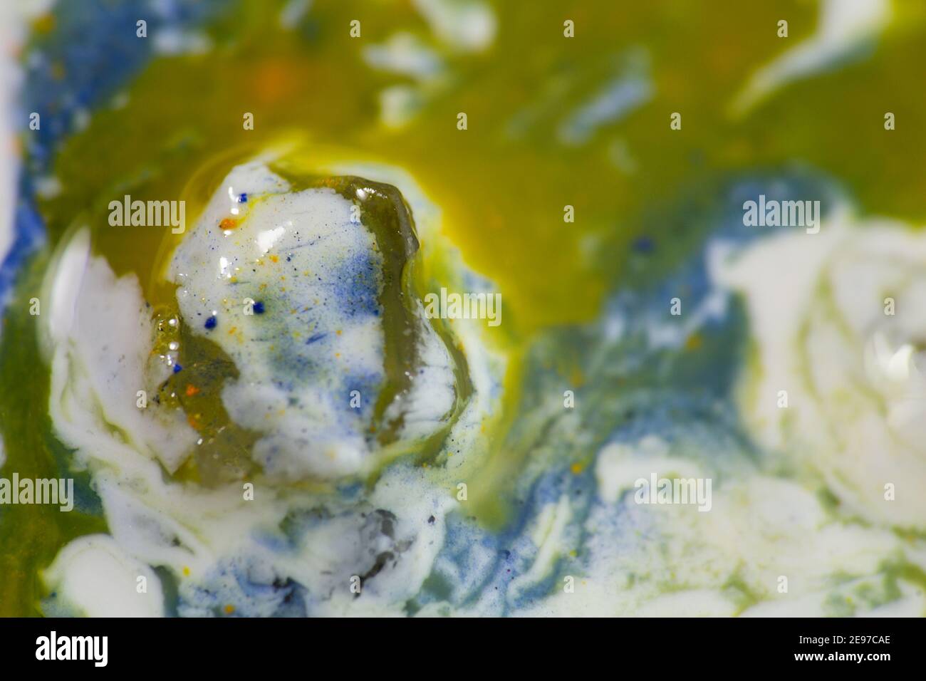 Luqiud vivid blue and ochre color mixing together on white background ...
