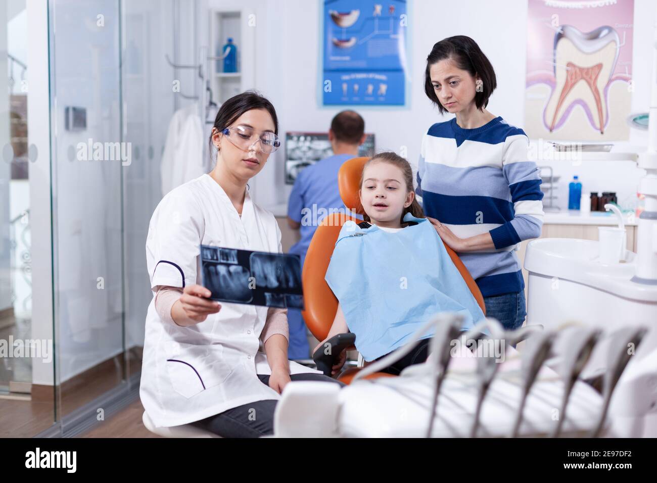 Dentist examining little kid radiography sitting on chair wearing ...