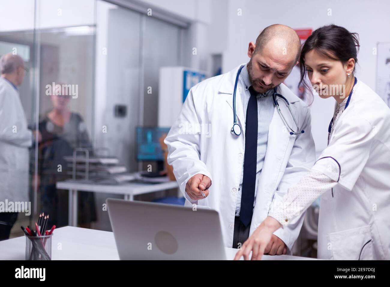 Worried team of young doctors pointing on laptop anlysing result of ...