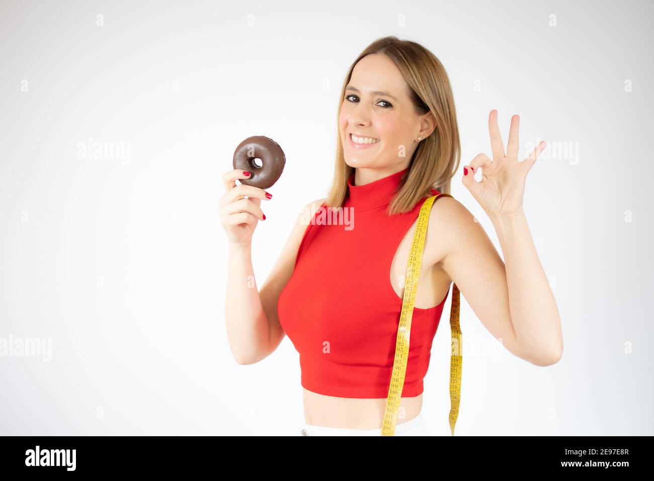 Woman Measuring Body Weight on weighing scale holding donuts Stock ...