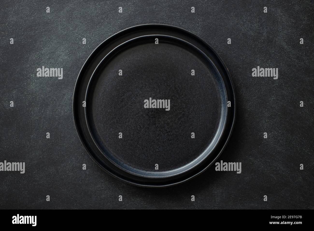 Empty black plates on black stone table. Top view Stock Photo - Alamy