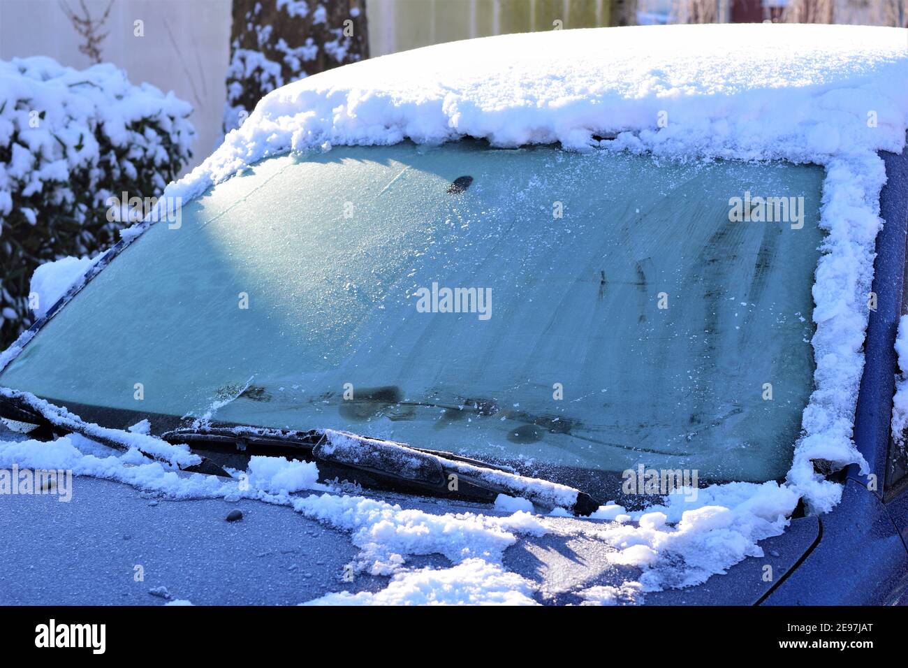 Iced snow on a blue car with a, icy windshield in the sunlight as a ...