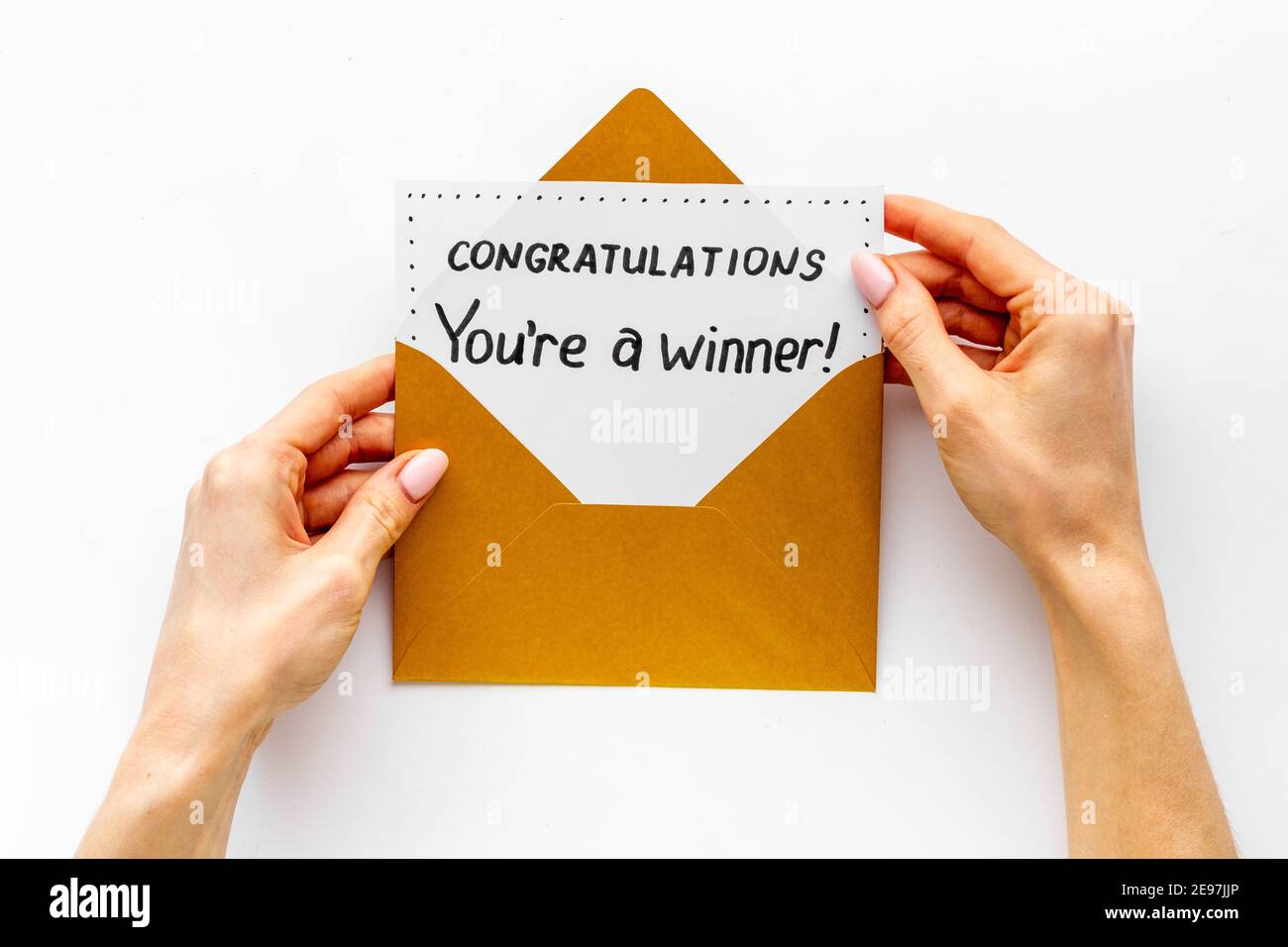 Hands holding award congratulation card in golden envelope. Text You're ...