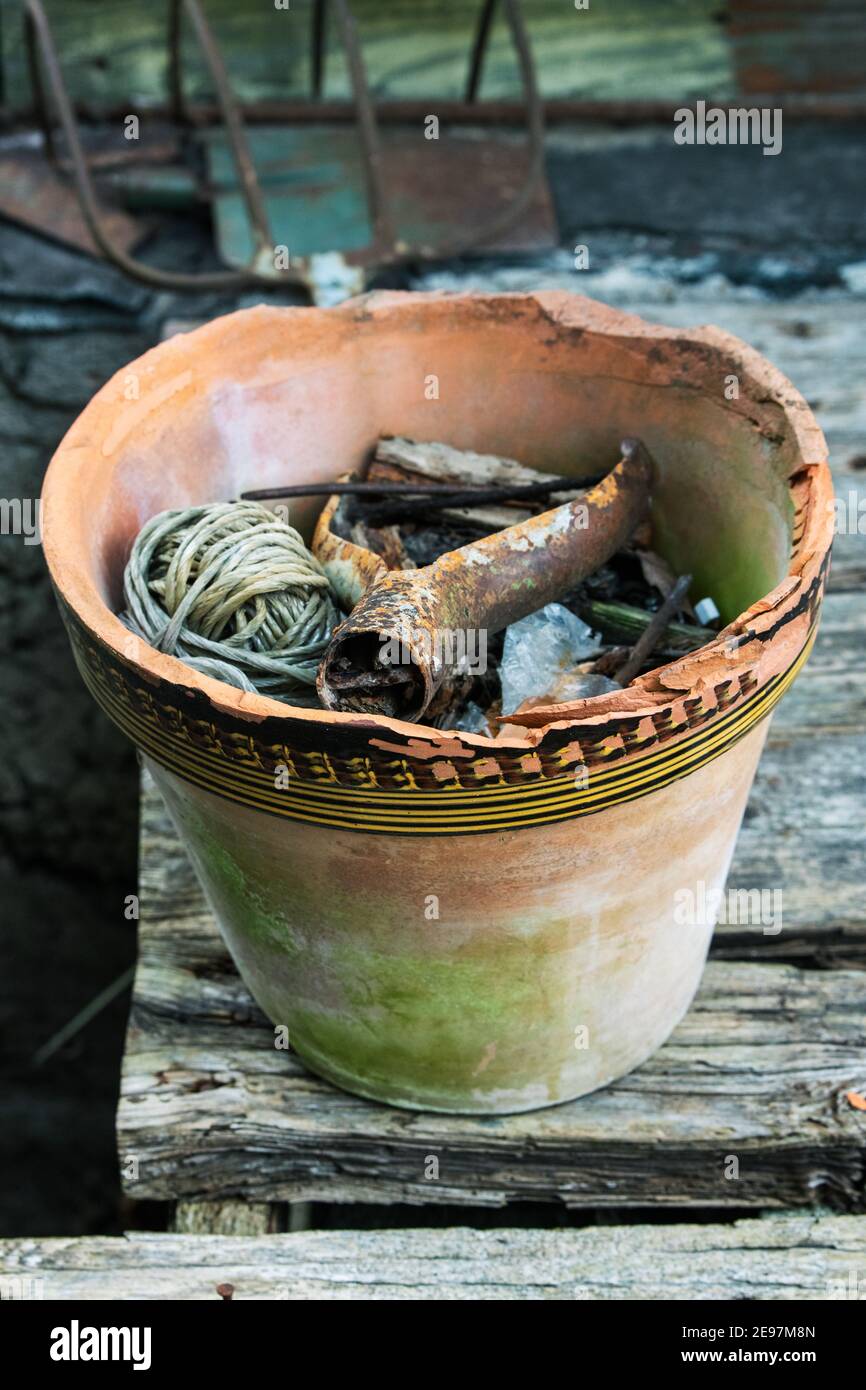 Old plant pot with other stuff dumped in Stock Photo - Alamy