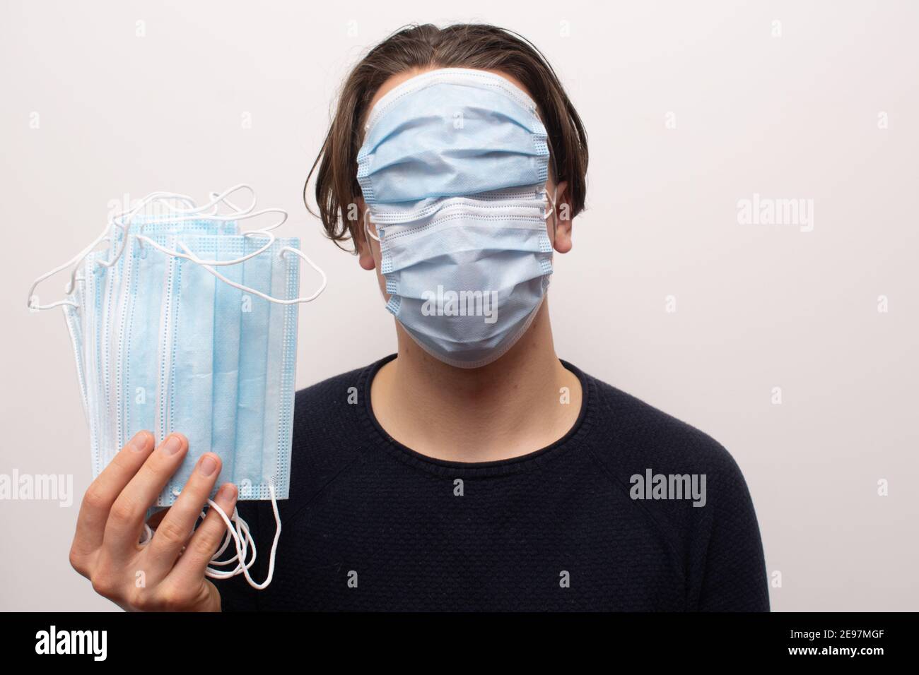 Men showing his many face masks on white background with two masks on ...