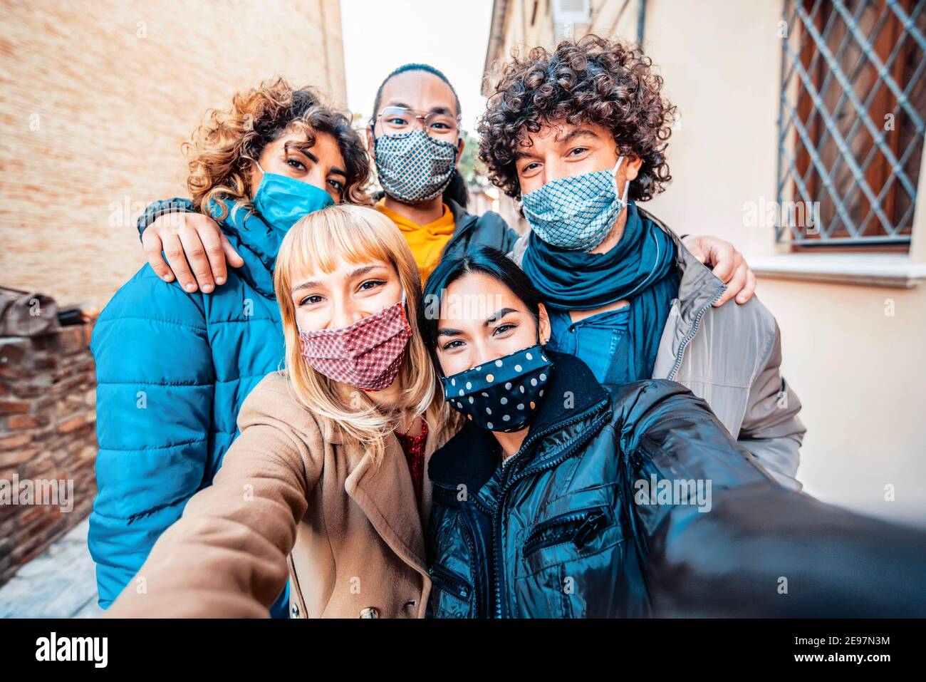 Multiracial friends covered by face mask taking selfie wearing winter ...