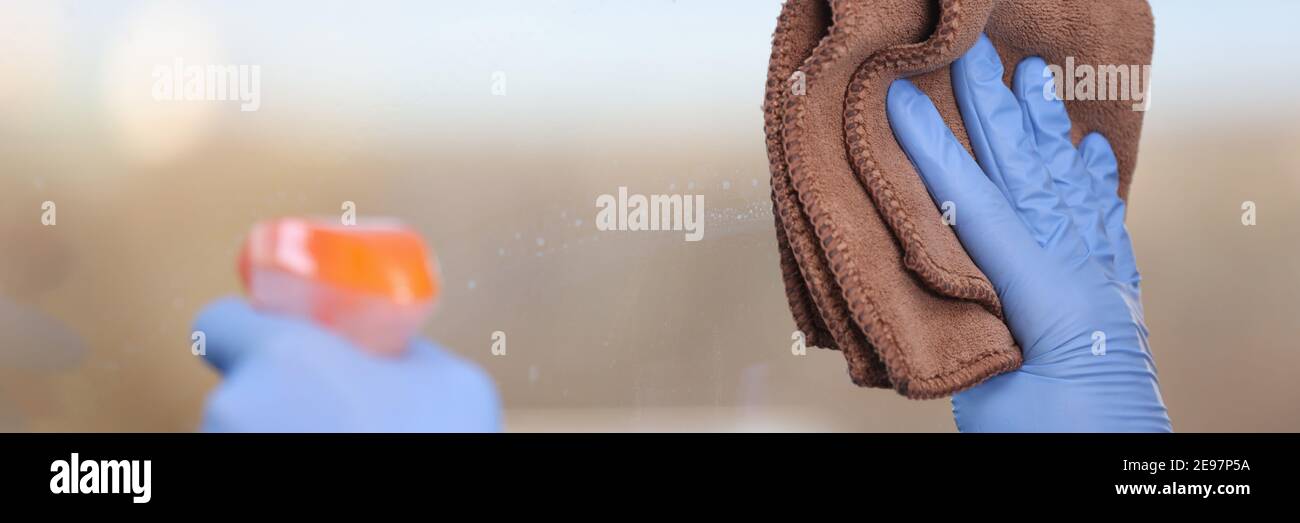 Man washes window and holds rag and cleaning agent Stock Photo - Alamy