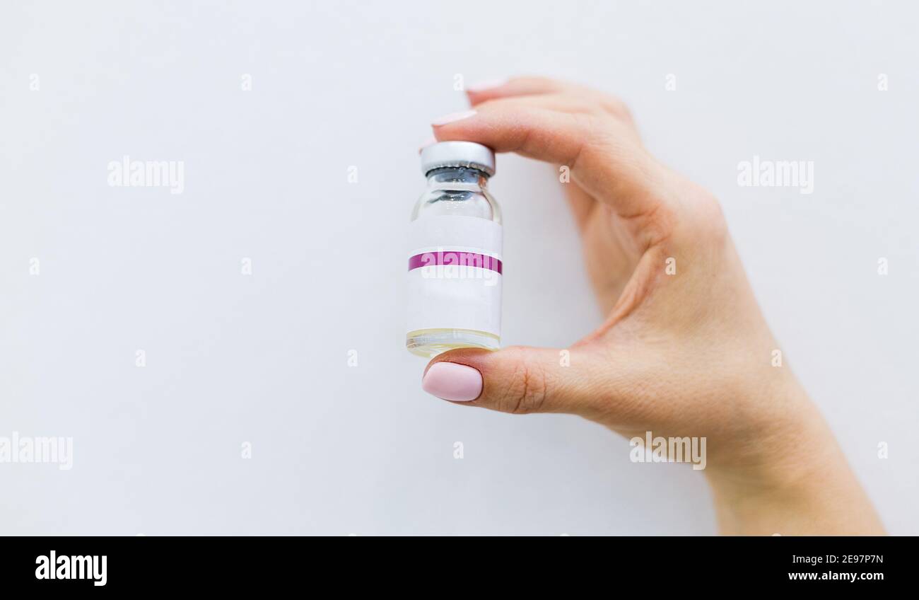 Close-up of a female hand holding an ampoule container with a ...