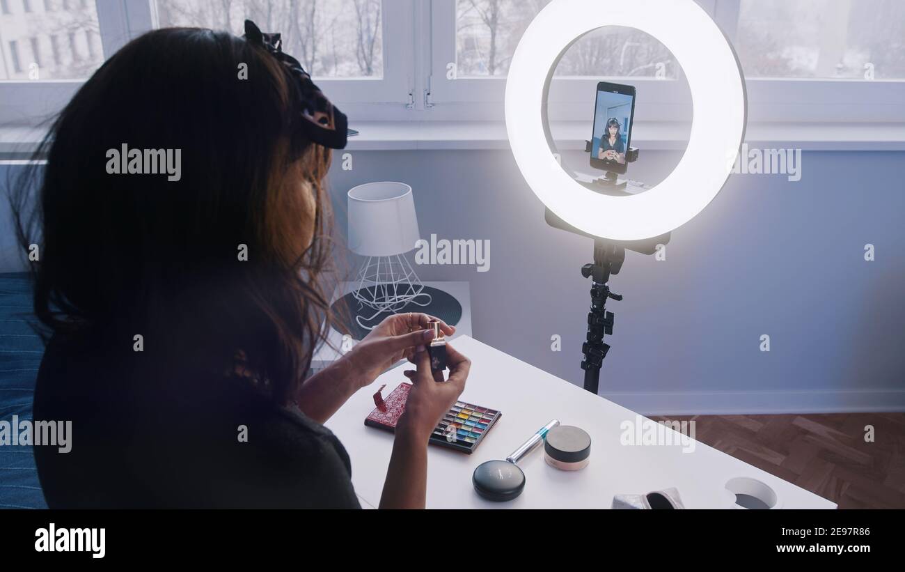 Young woman with black hair recording make up tutorial. Applying make ...