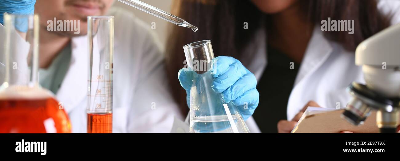 Scientists in laboratory hold flask and drip clear liquid into it Stock ...