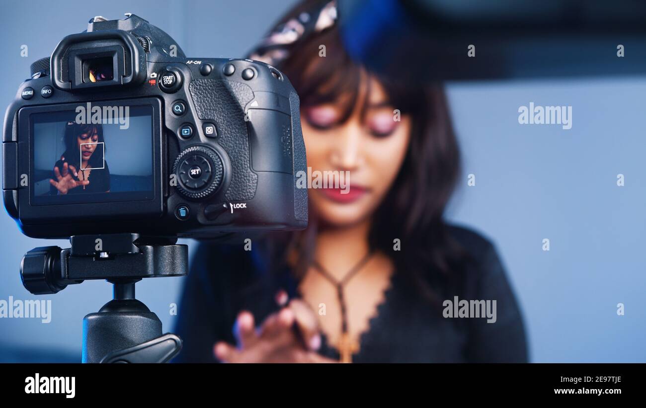 Young woman with black hair applying make up in front of the camera ...