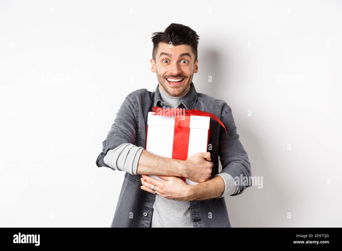 Happy caucasian man holding surprise gift, hugging present and smiling ...