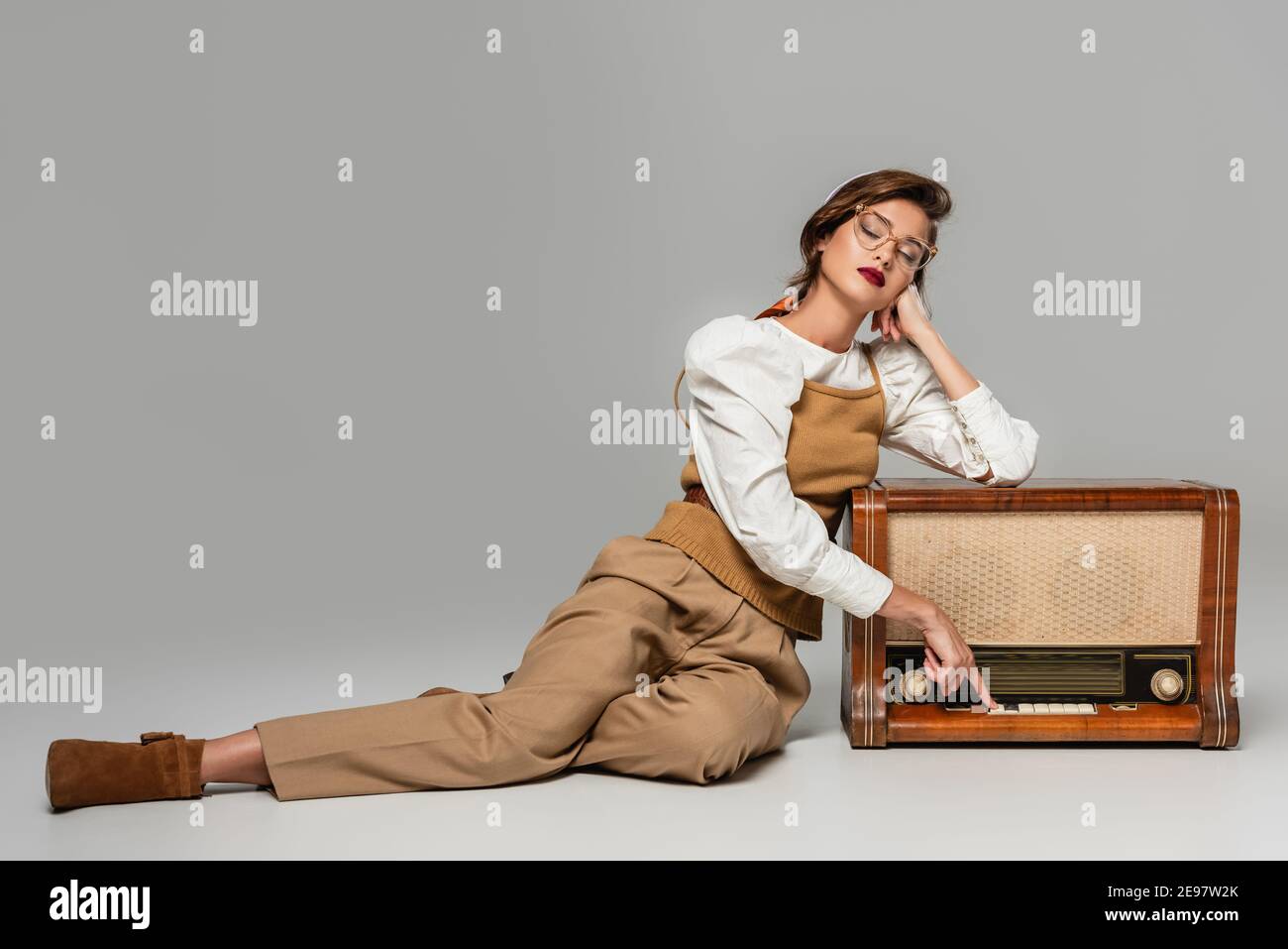 pretty trendy woman pressing button on vintage radio receiver while ...