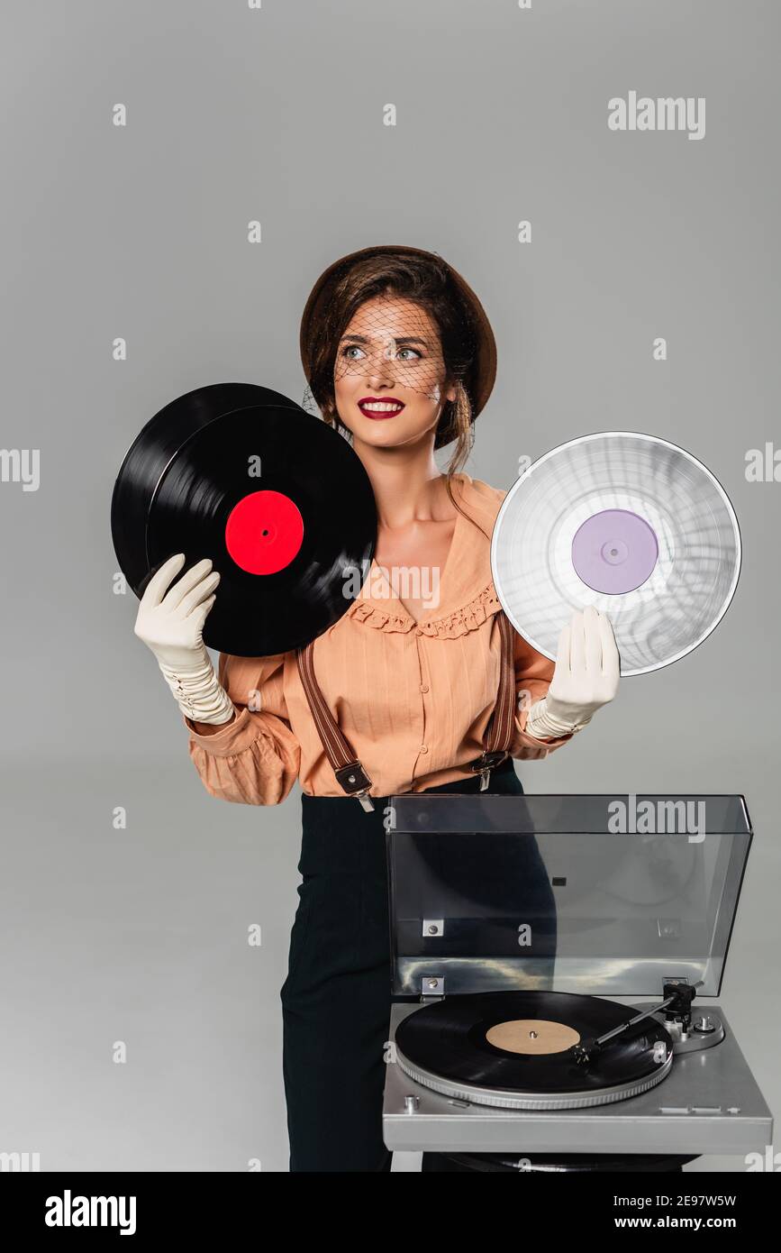 happy woman in vintage clothes holding vinyl discs near record player ...