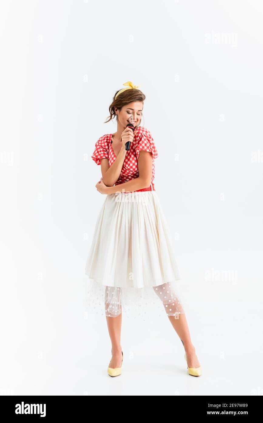 full length view of pin up woman with microphone singing with closed ...