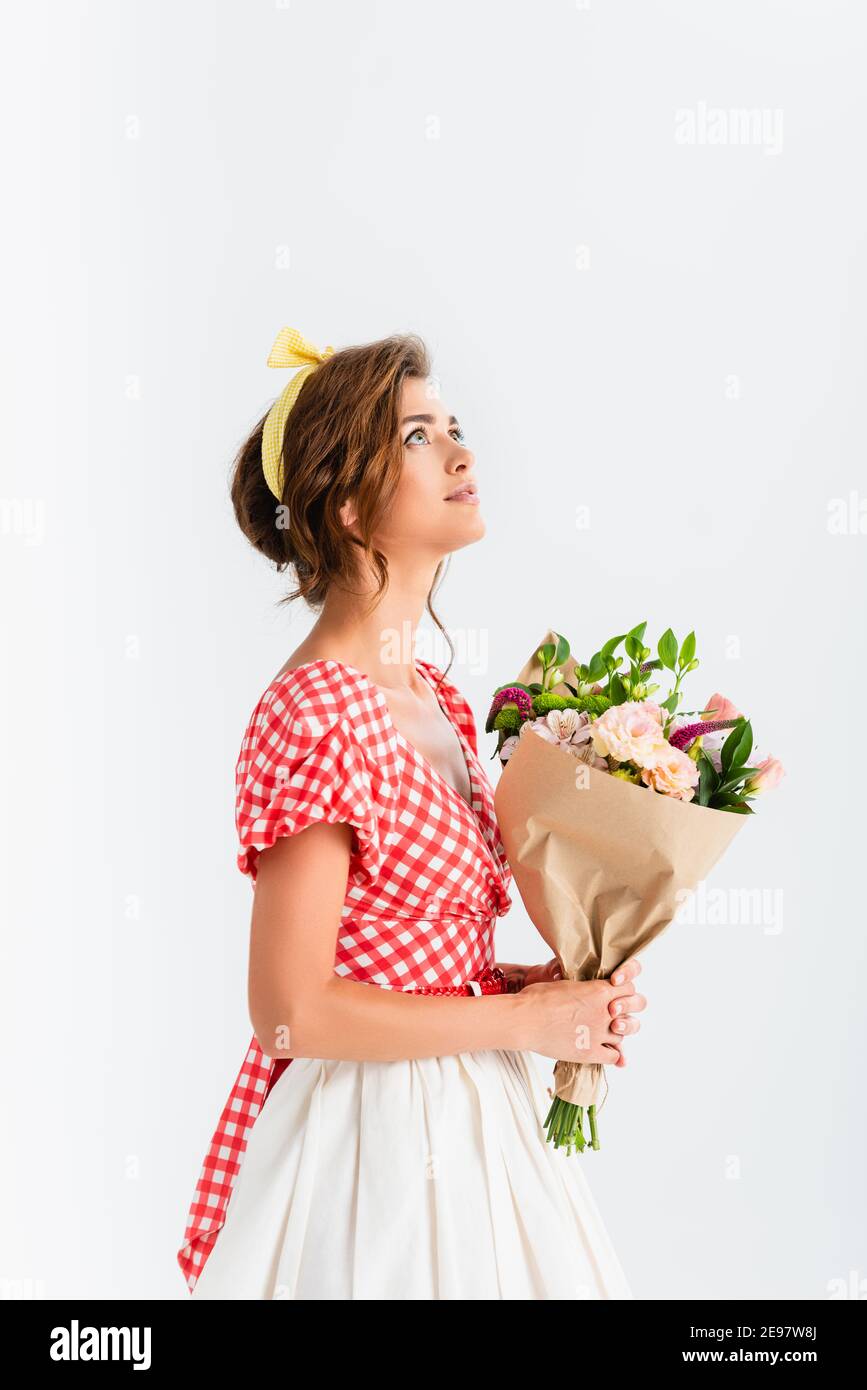 stylish pin up woman holding flowers and looking away isolated on white ...