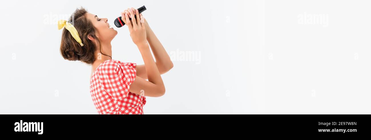 side view of pin up woman singing with microphone isolated on white ...