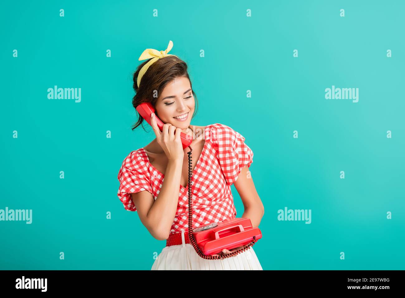 happy pin up woman talking on retro phone isolated on turquoise Stock ...