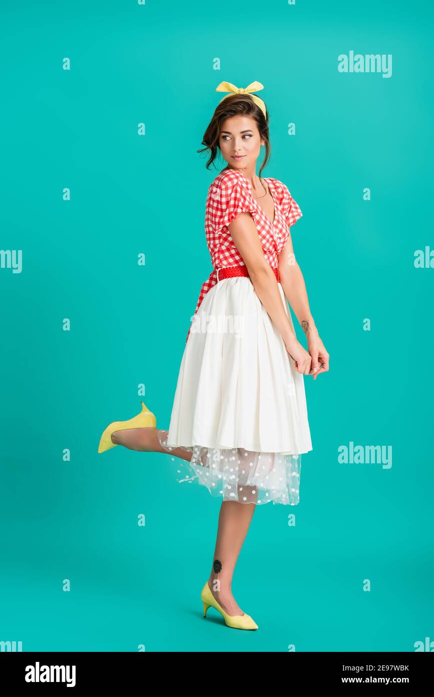 Coquettish Pin Up Woman Standing On One Leg While Posing On Turquoise
