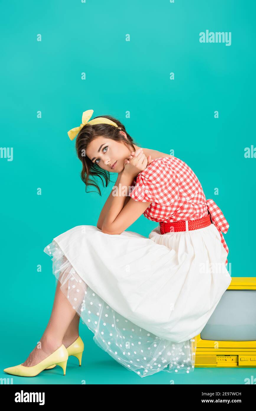 trendy pin up woman sitting on yellow retro tv and looking at camera on ...