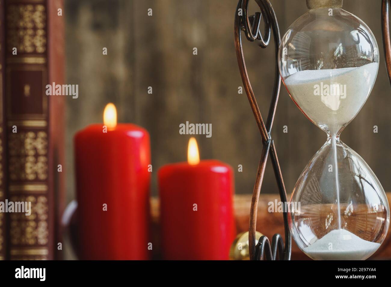 Hourglass and red burning candles close up Stock Photo - Alamy
