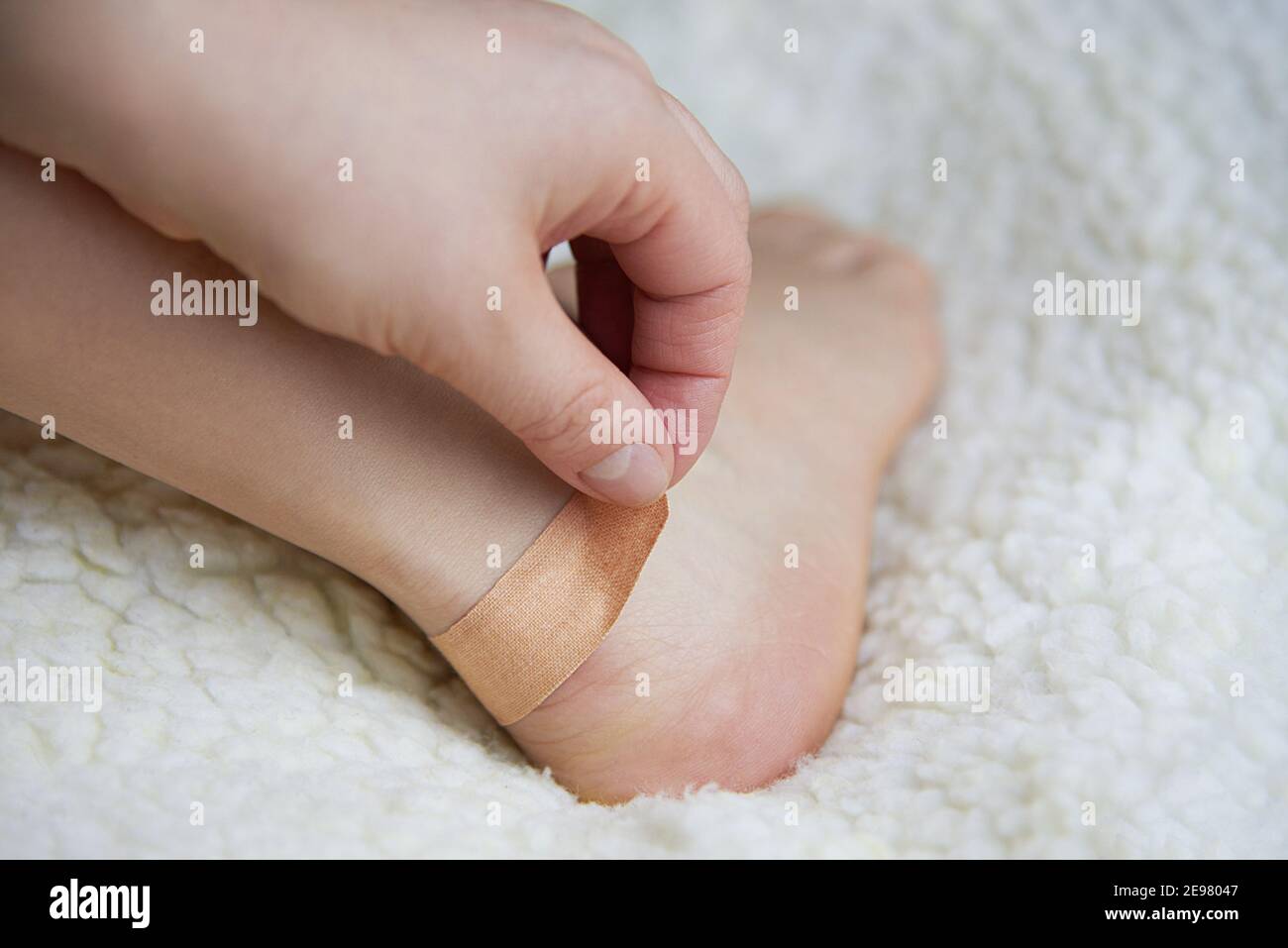 A woman glues a tissue plaster to a corn on her leg Stock Photo - Alamy