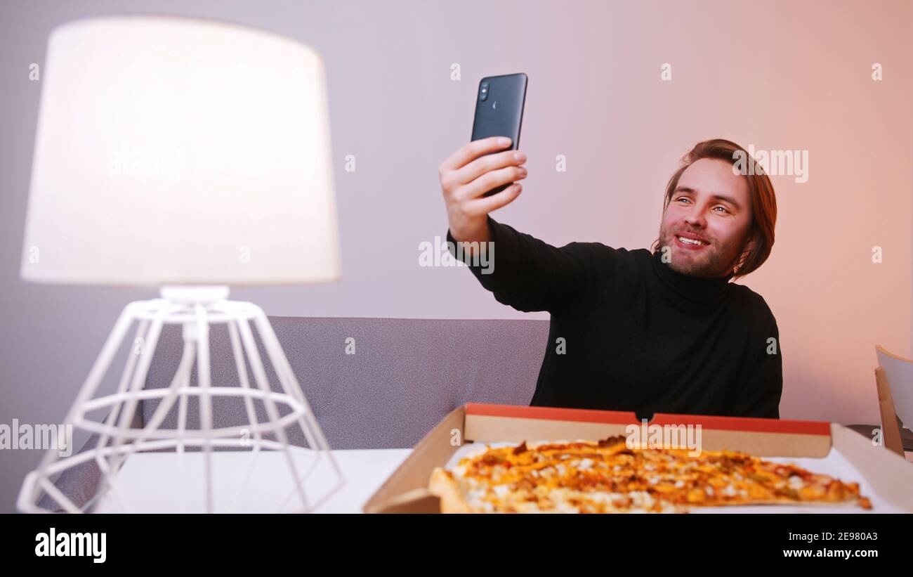Young caucasian man having video call on his smartphone while having ...