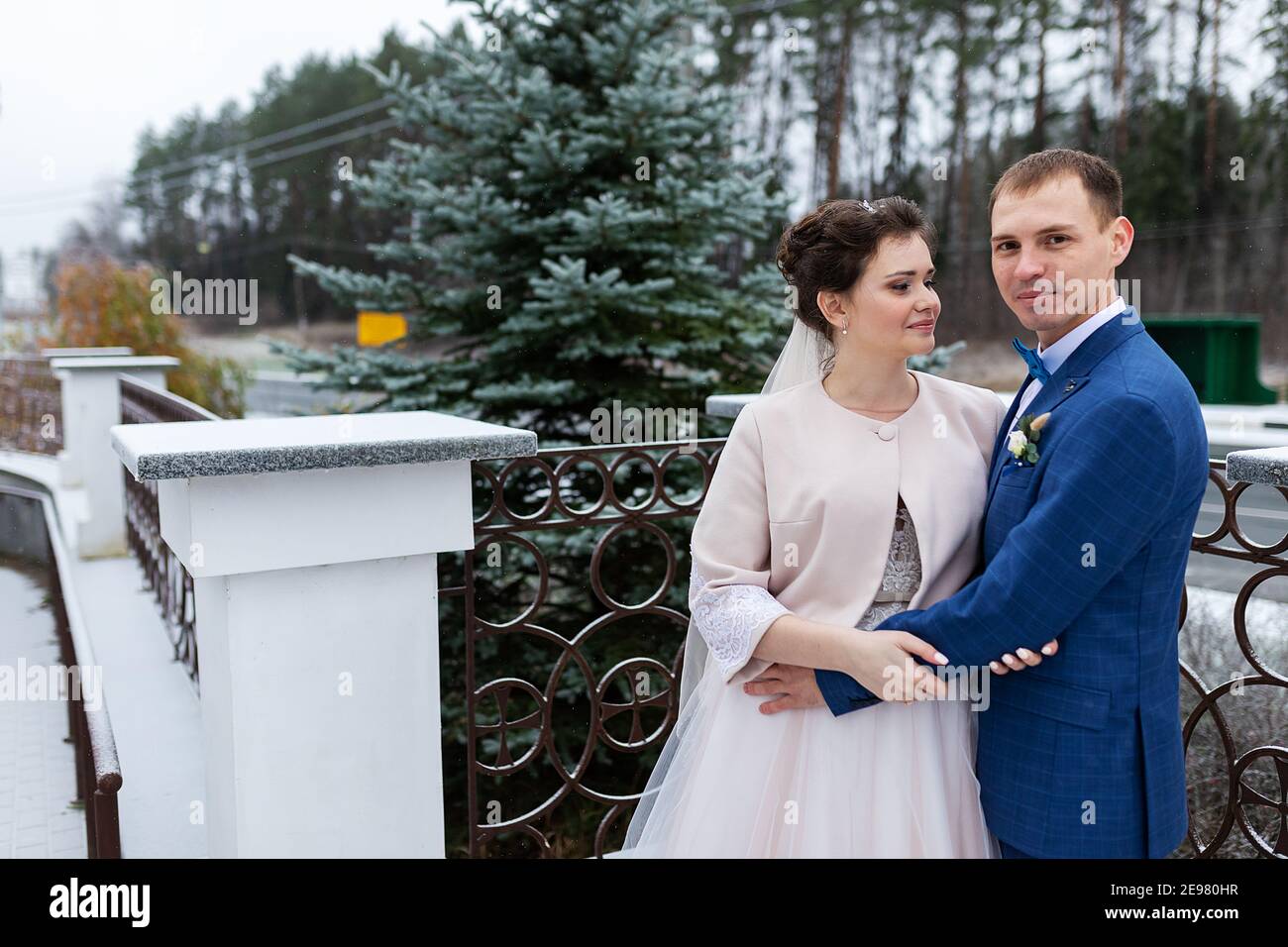 two newlyweds on a wedding walk in winter, lovers happily hug and ...