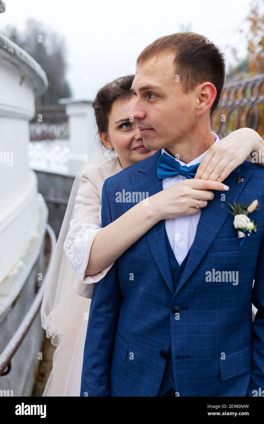 two newlyweds on a wedding walk in winter, lovers happily hug and ...