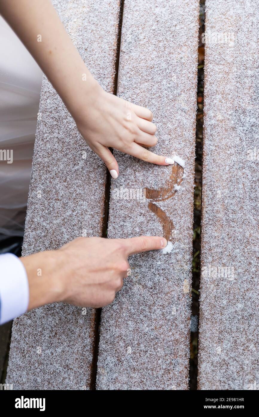 two lovers draw with their fingers in the snow, draw hearts in the snow ...