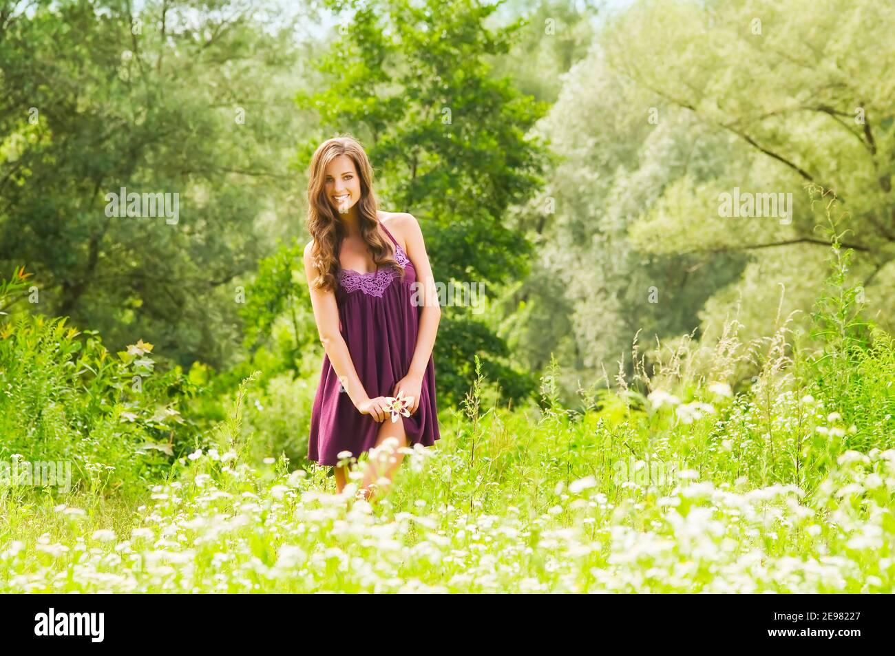 Smiling young woman in burgundy dress with flower against background of ...