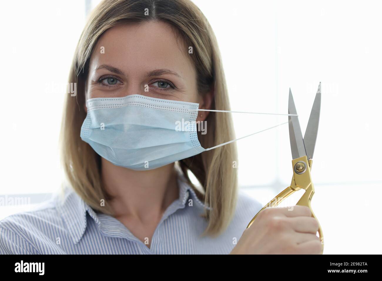 Woman cutting protective medical mask on her face with scissors Stock ...