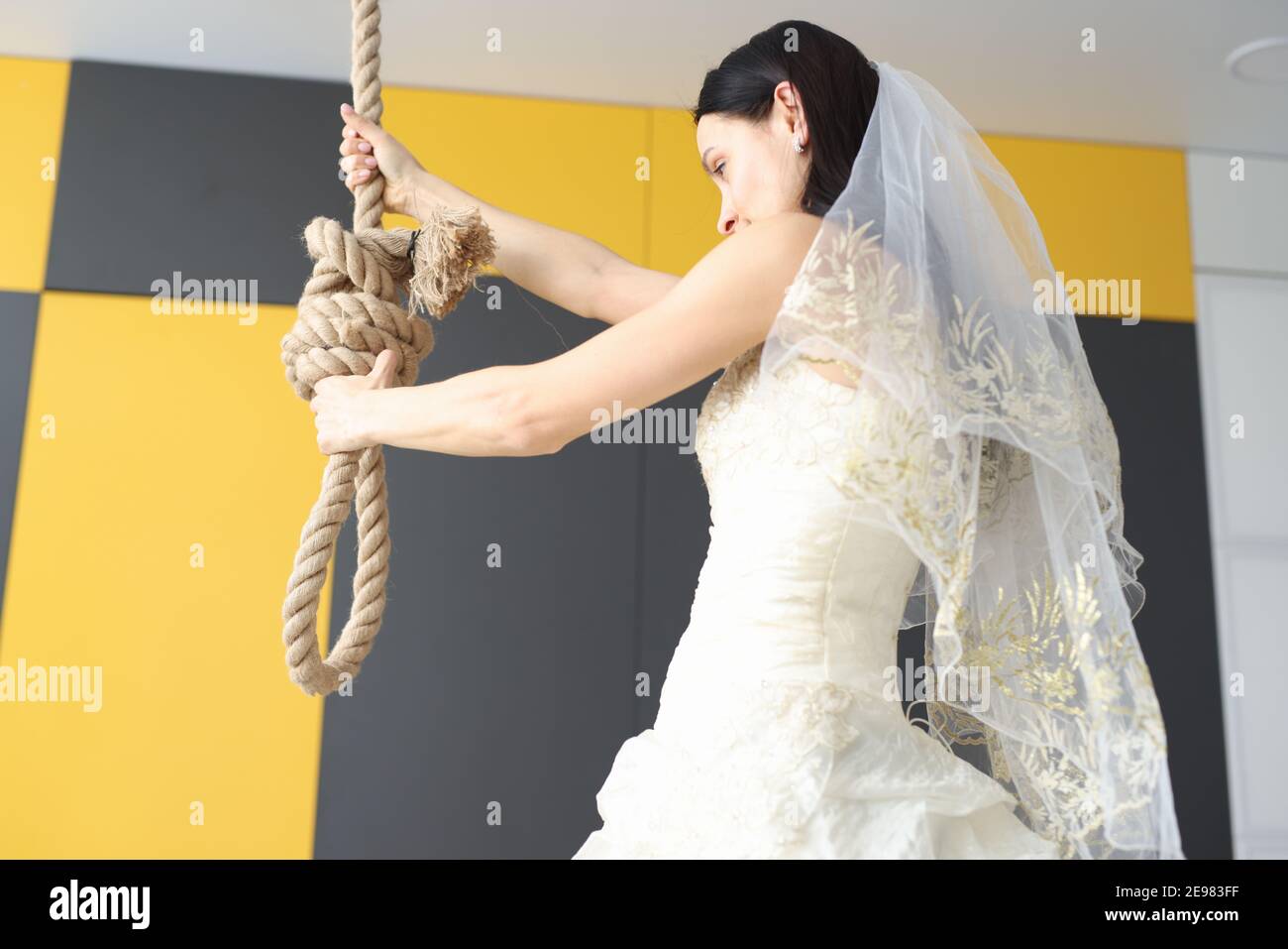 Bride in wedding dress holding rope for suicide Stock Photo - Alamy