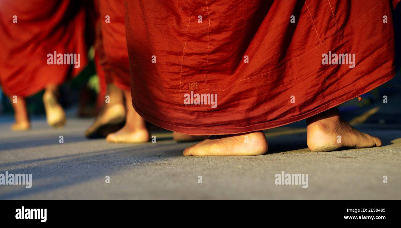 feet of monks dressing orange robe during reception of alms, around ...