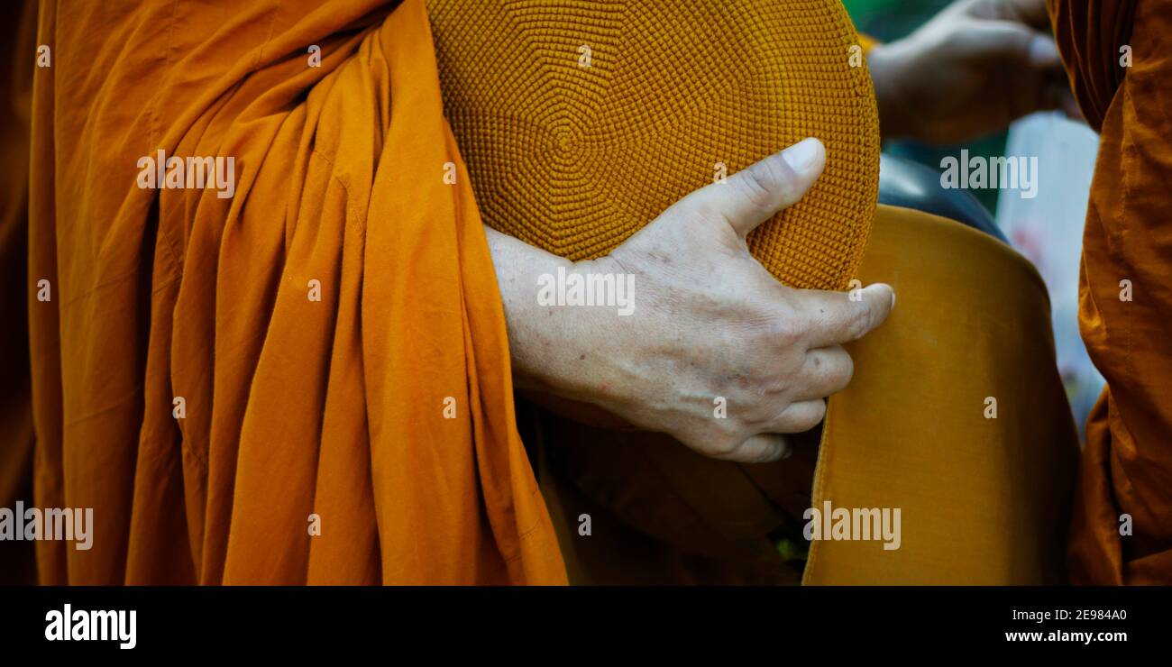hand of monk dressing orange robe, holding bowl during reception of ...
