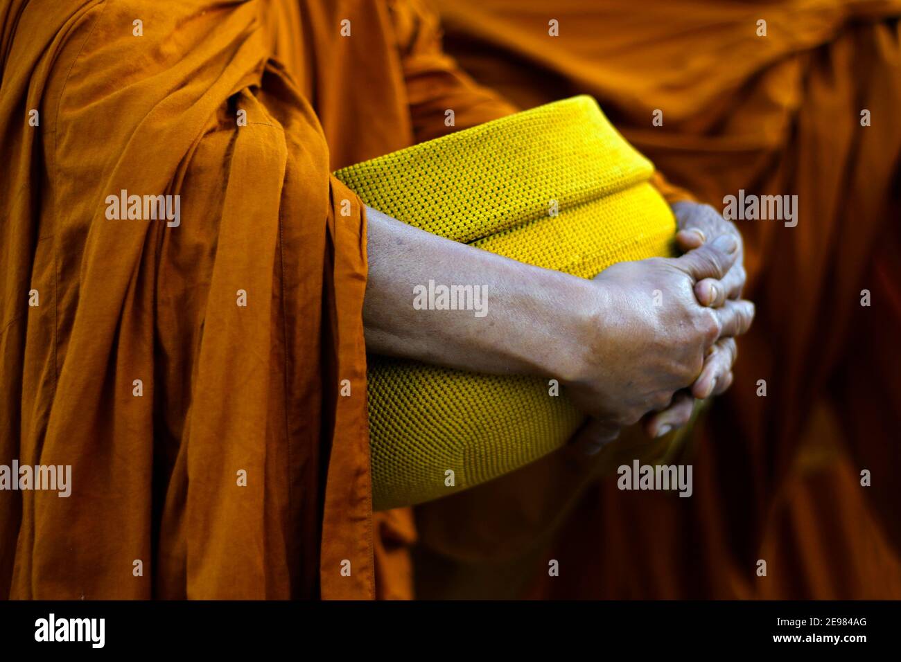 hand of monk dressing orange robe, holding bowl during reception of ...
