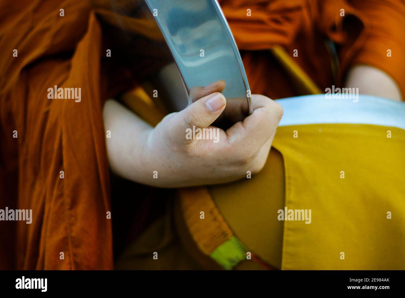 hand of monk dressing orange robe, holding bowl during reception of ...