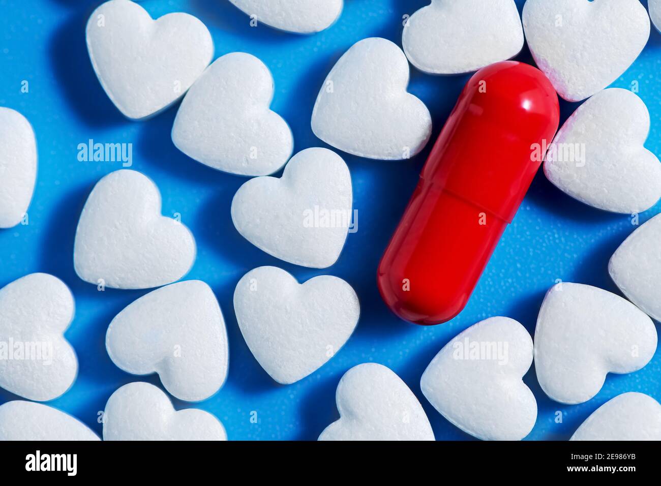 heart-shaped tablets and red pill. on blue background. medicine ...