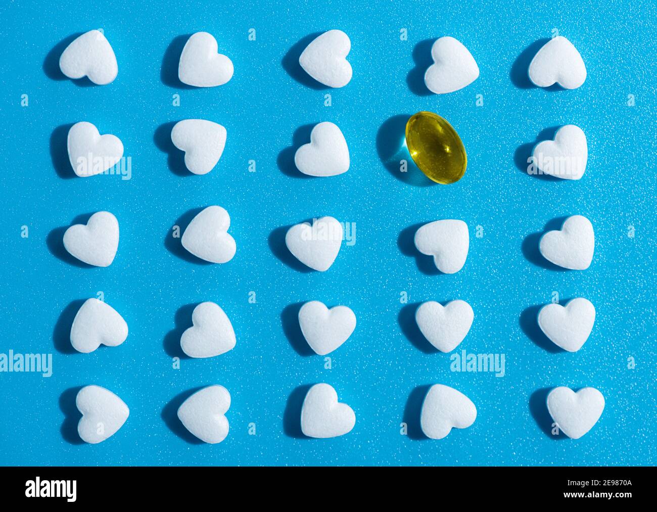 heart-shaped tablets and yellow gelatin pill. pattern on blue ...