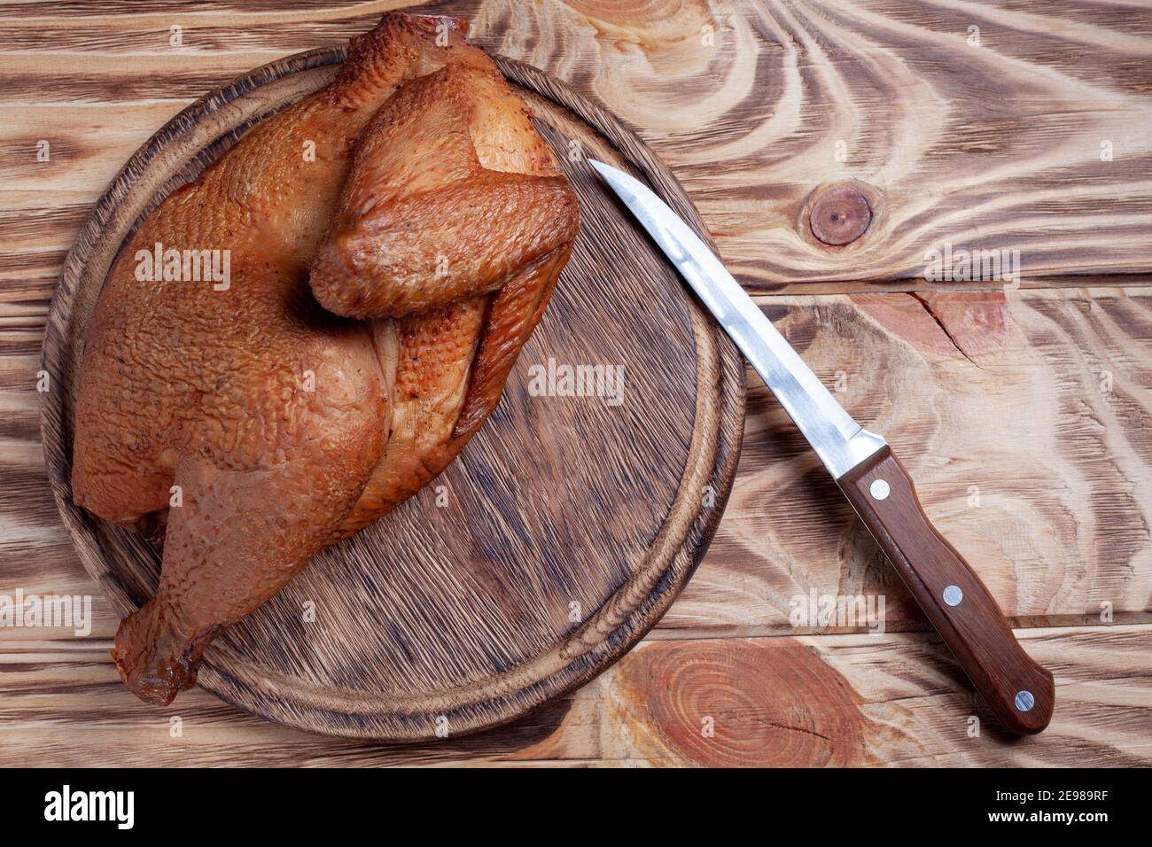 grilled half chicken on wooden cutting board with sharp knife. fried ...