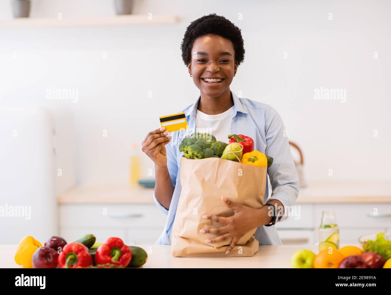 Woman Holding Credit Card And Grocery Shopping Bag In Kitchen Stock ...