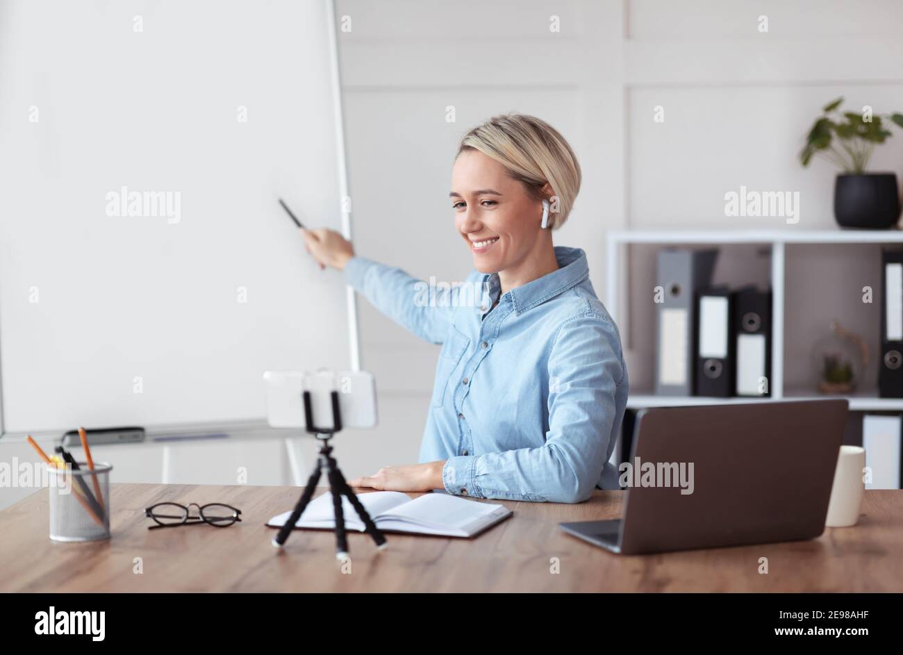 Joyful young teacher giving online private lesson from home, pointing ...