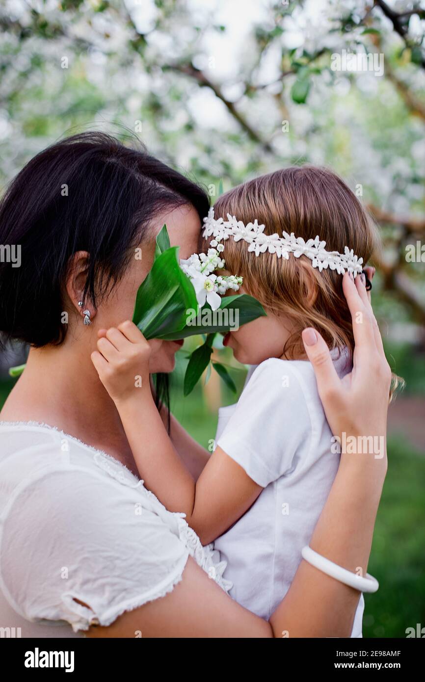Cute daughter and mother hugging in blossom spring garden Happy woman ...