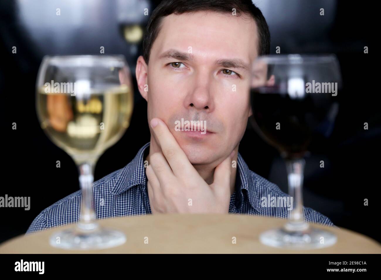 Choosing alcohol, man looks at the glasses with white and red wine ...
