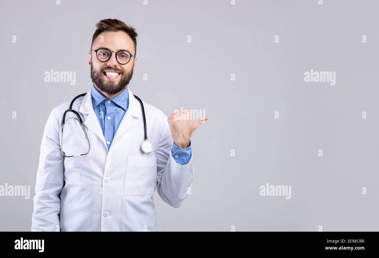 Positive Caucasian male doctor in lab coat showing thumb up gesture and ...