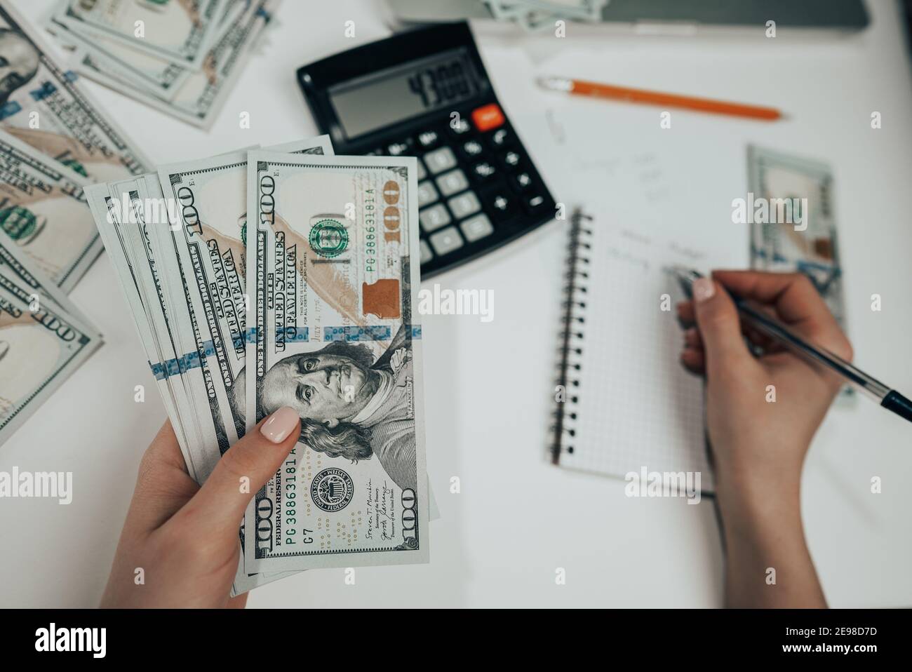 Unrecognizable woman holding money in hands and calculates income on ...