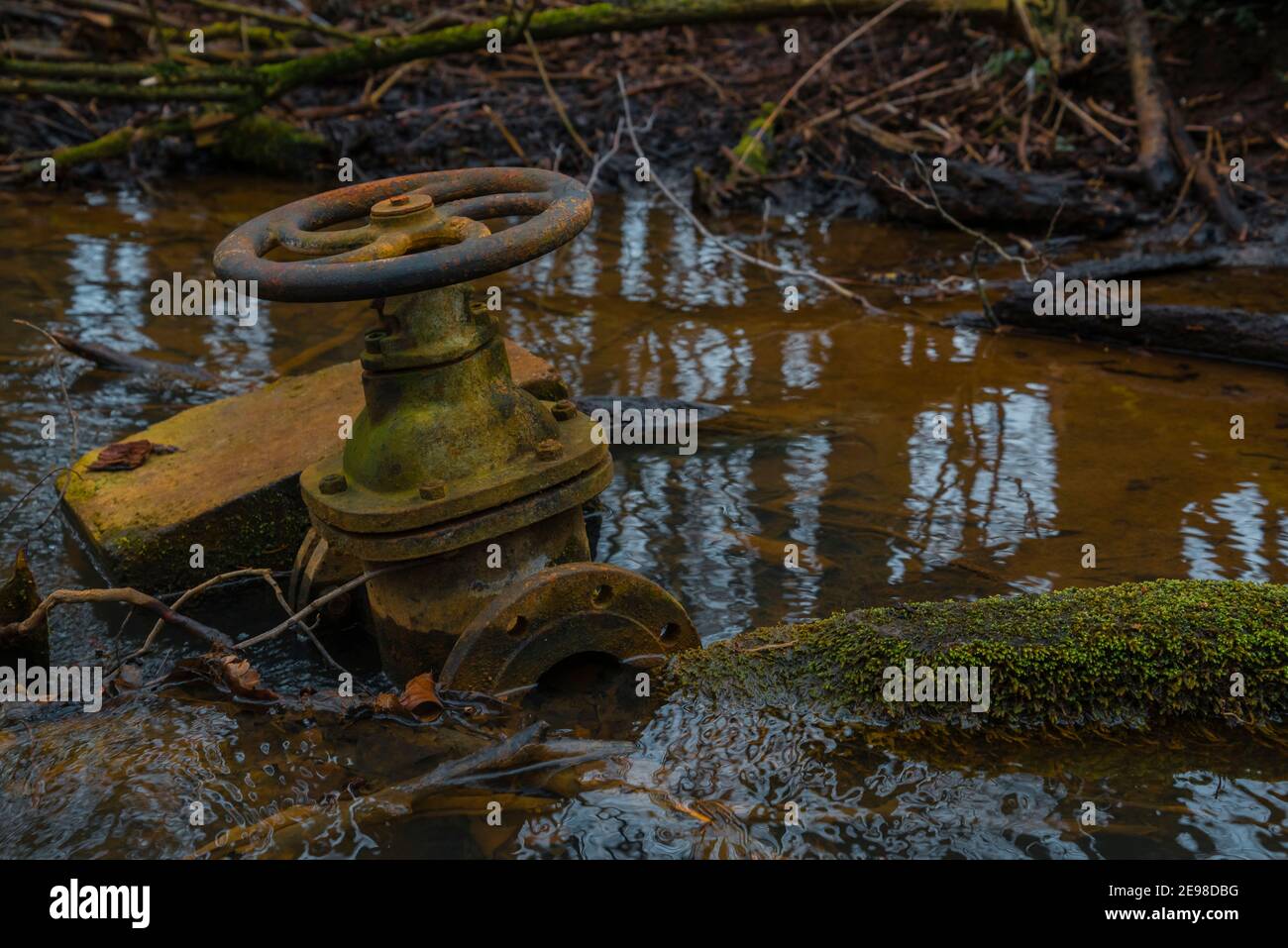 A big faucet is in a shallow river, A shut-off valve is in the water ...