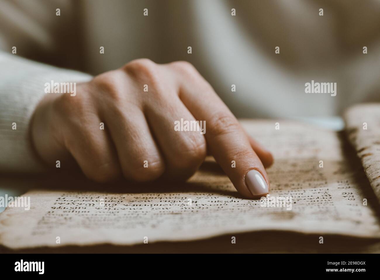 Woman reading ancient book - Bible. Concentrated attentively follows ...